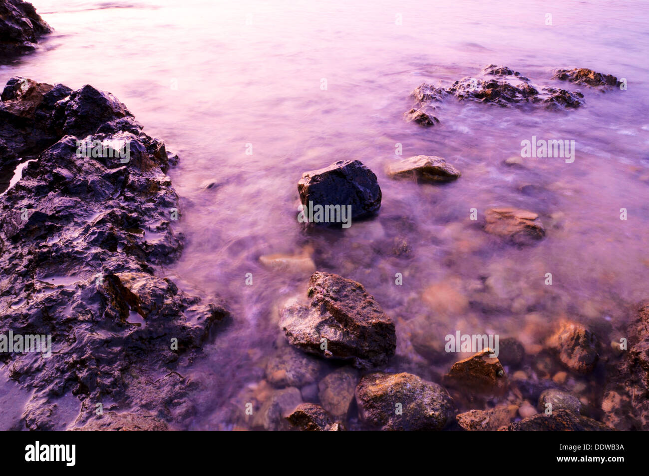 Stones and purple sea water in the long exposure Stock Photo - Alamy