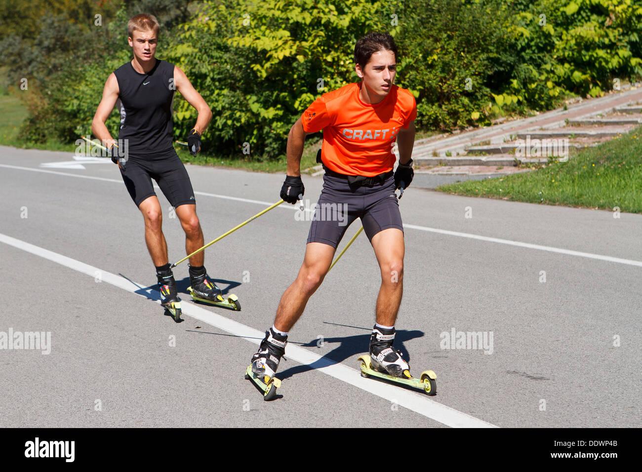 Two young man practicing roller skiing in the park (as a summer ...