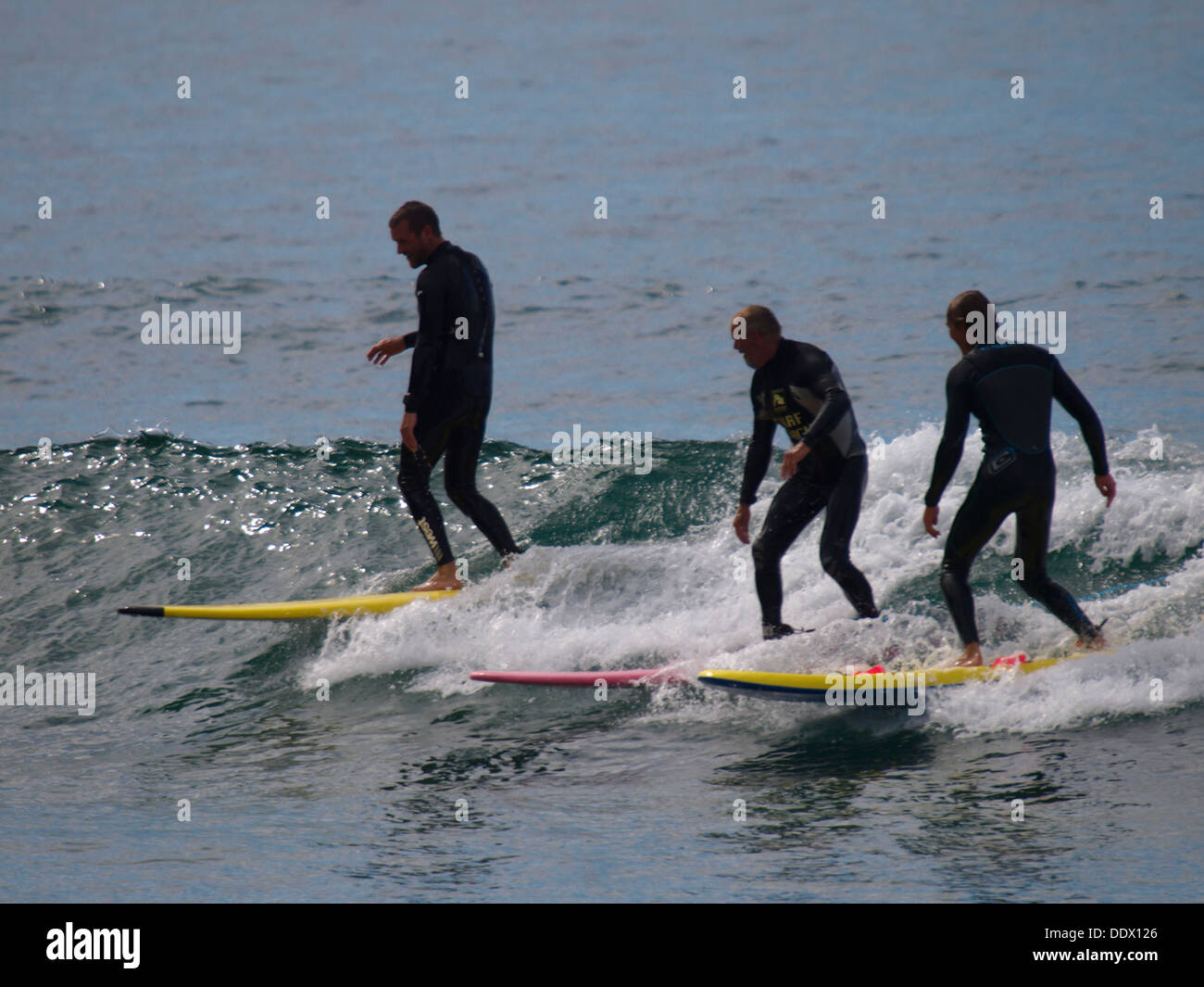 Three surfers on the same wave, Trebarwith Strand, Cornwall, UK 2013 ...