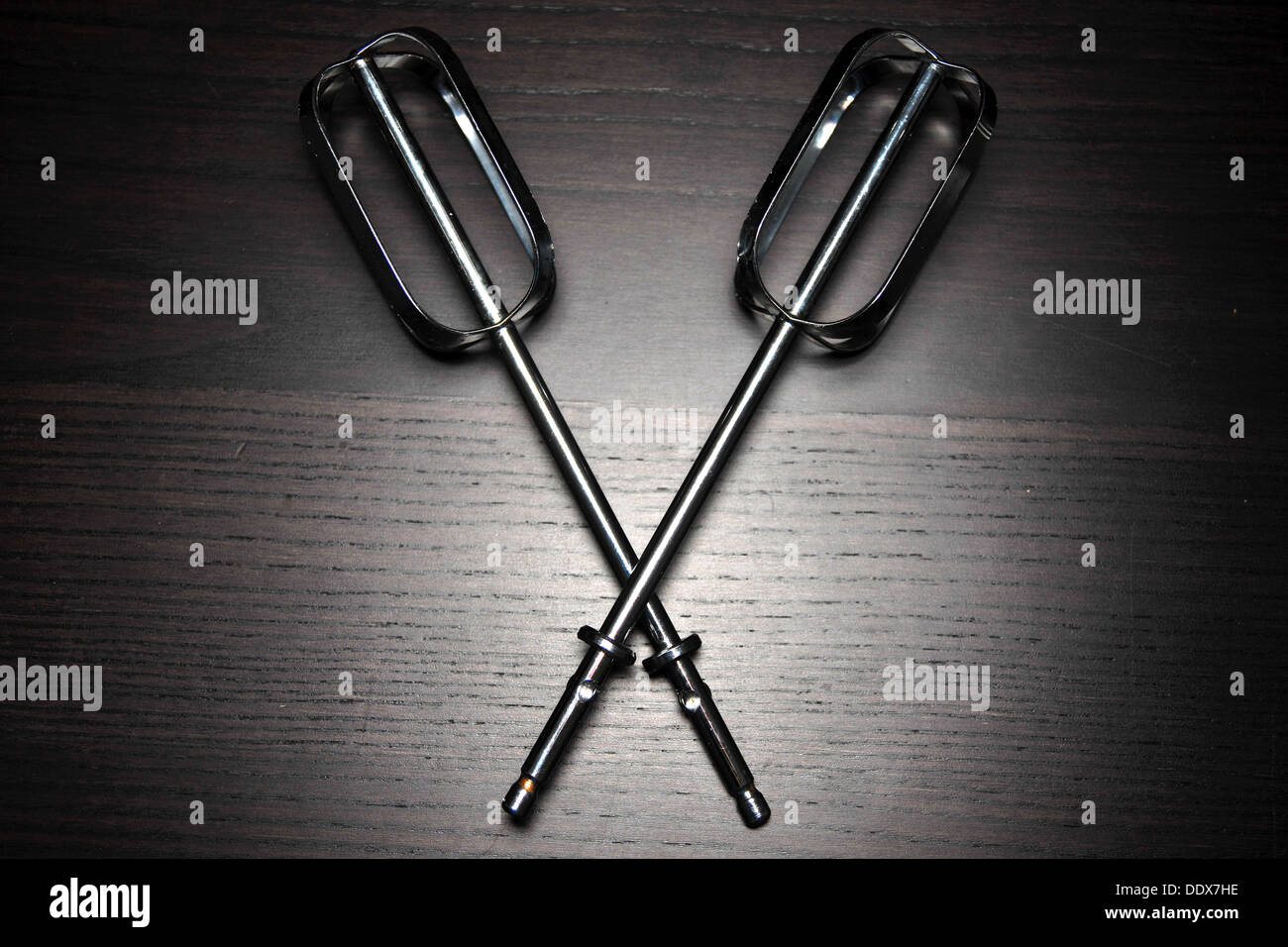 A pair of metal whisks photographed against a black background Stock ...