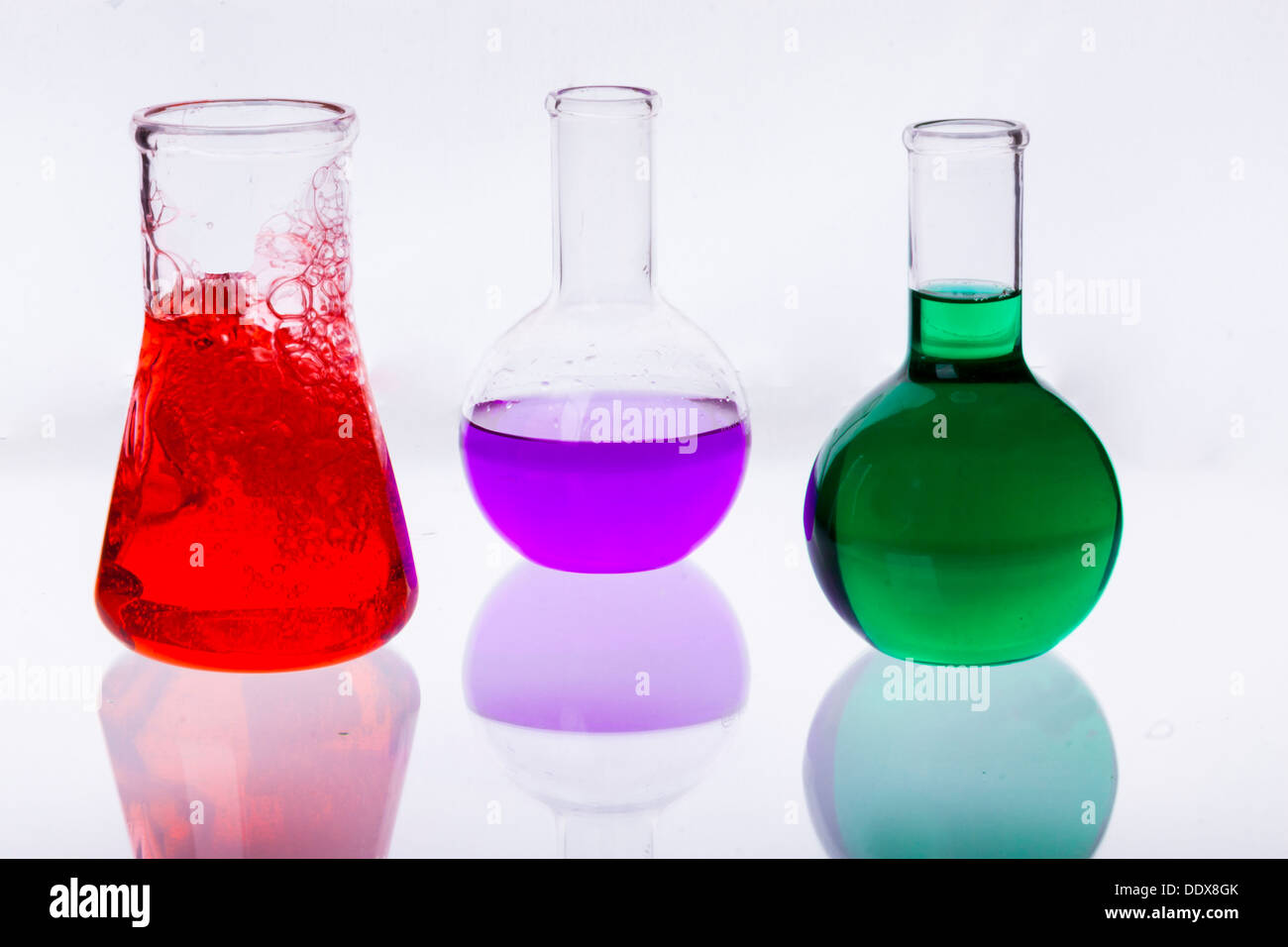 Laboratory glassware with liquids of different colors on white ...