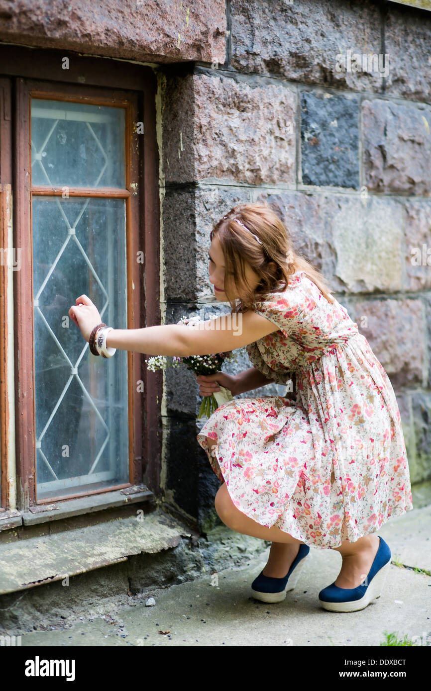 Woman in flowered dress knocking on window glass Stock Photo - Alamy