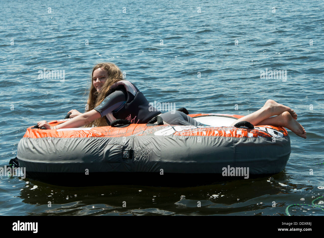 Girl lying on an inflatable raft in a lake, Lake of The Woods, Keewatin ...