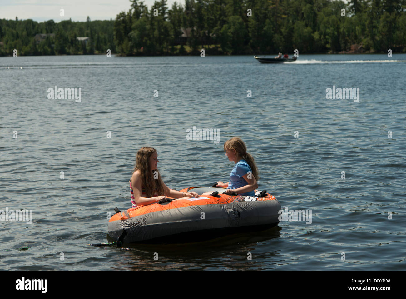 Girls sitting on an inflatable raft in a lake, Lake of The Woods ...