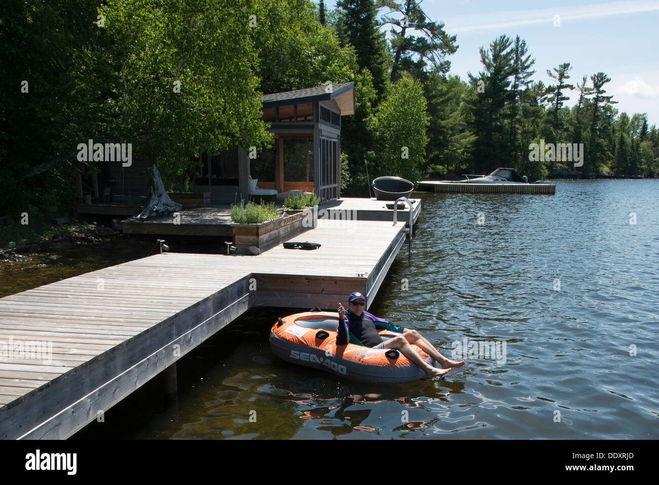 Man sitting on an inflatable raft floating in a lake, Lake of The Woods ...