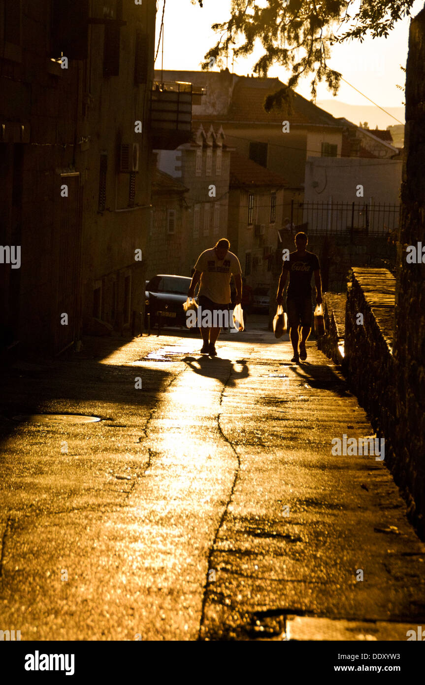 Backlit two men carrying plastic shopping bags in Split Croatia Stock ...