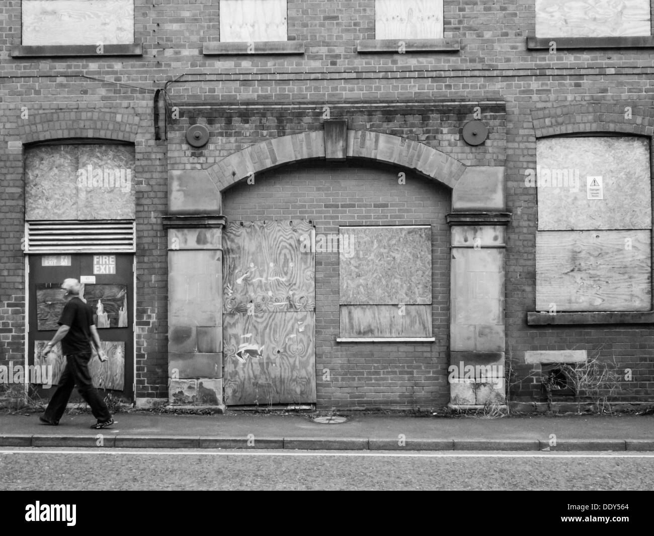 Man walking through the frame in front of an old abandoned and derelict ...