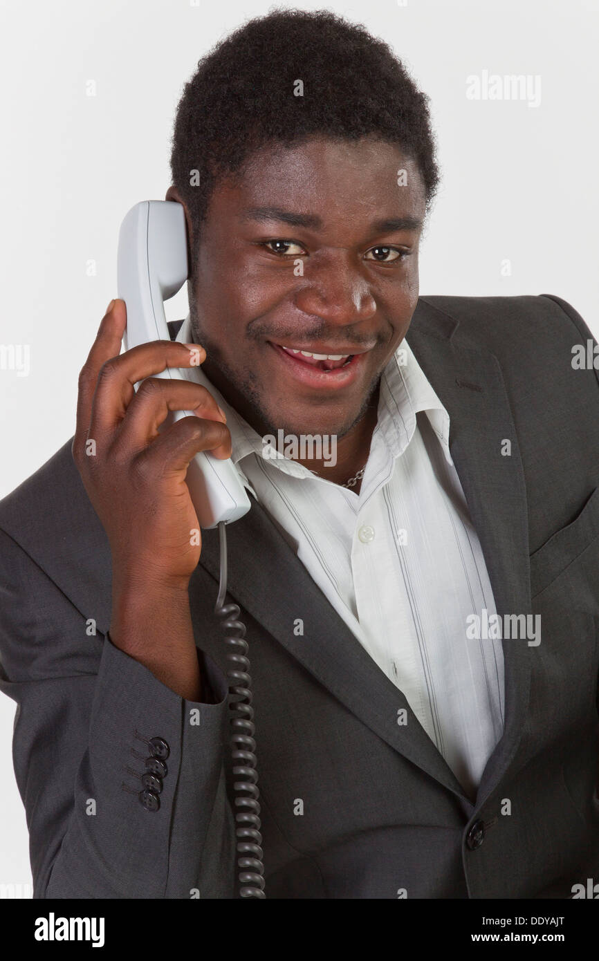 Young black man in a suit making a phone call in an office, smiling ...
