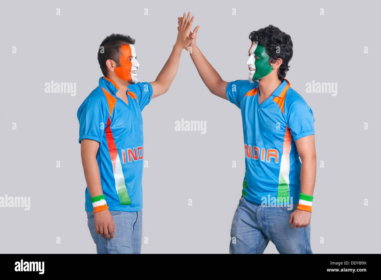 Male cricket fans with face painted in Indian tricolor giving a high ...