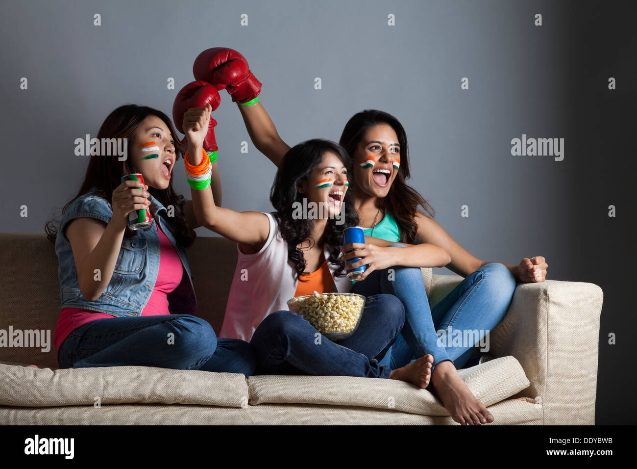 Excited young female friends watching boxing match together at home ...