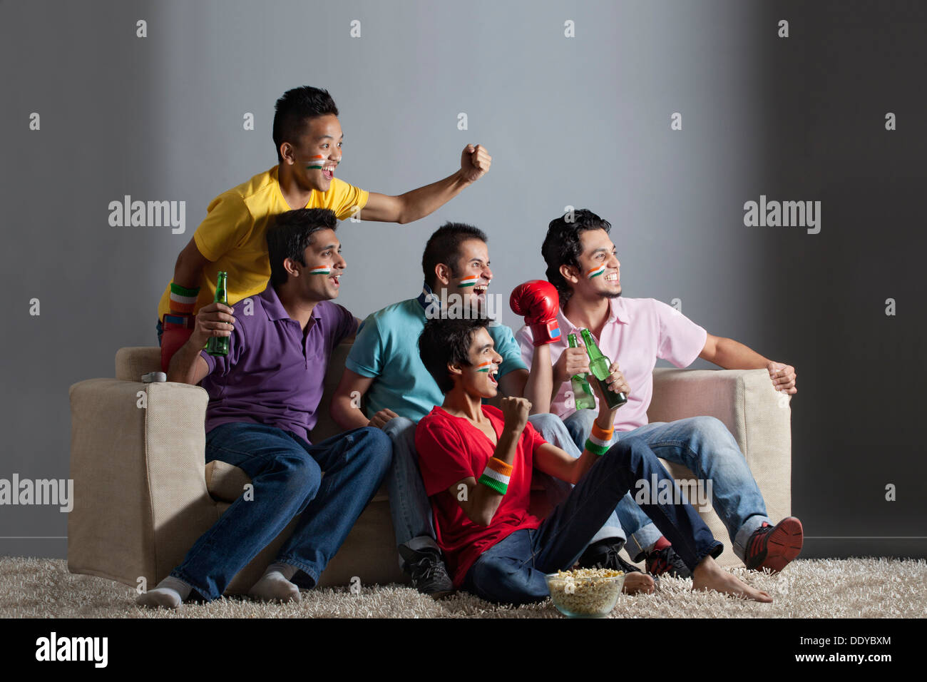 Excited male friends cheering out while watching boxing match together ...