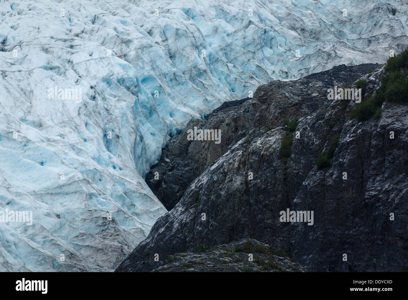 blue ice of glacier surrounding rugged stone mountain Stock Photo - Alamy