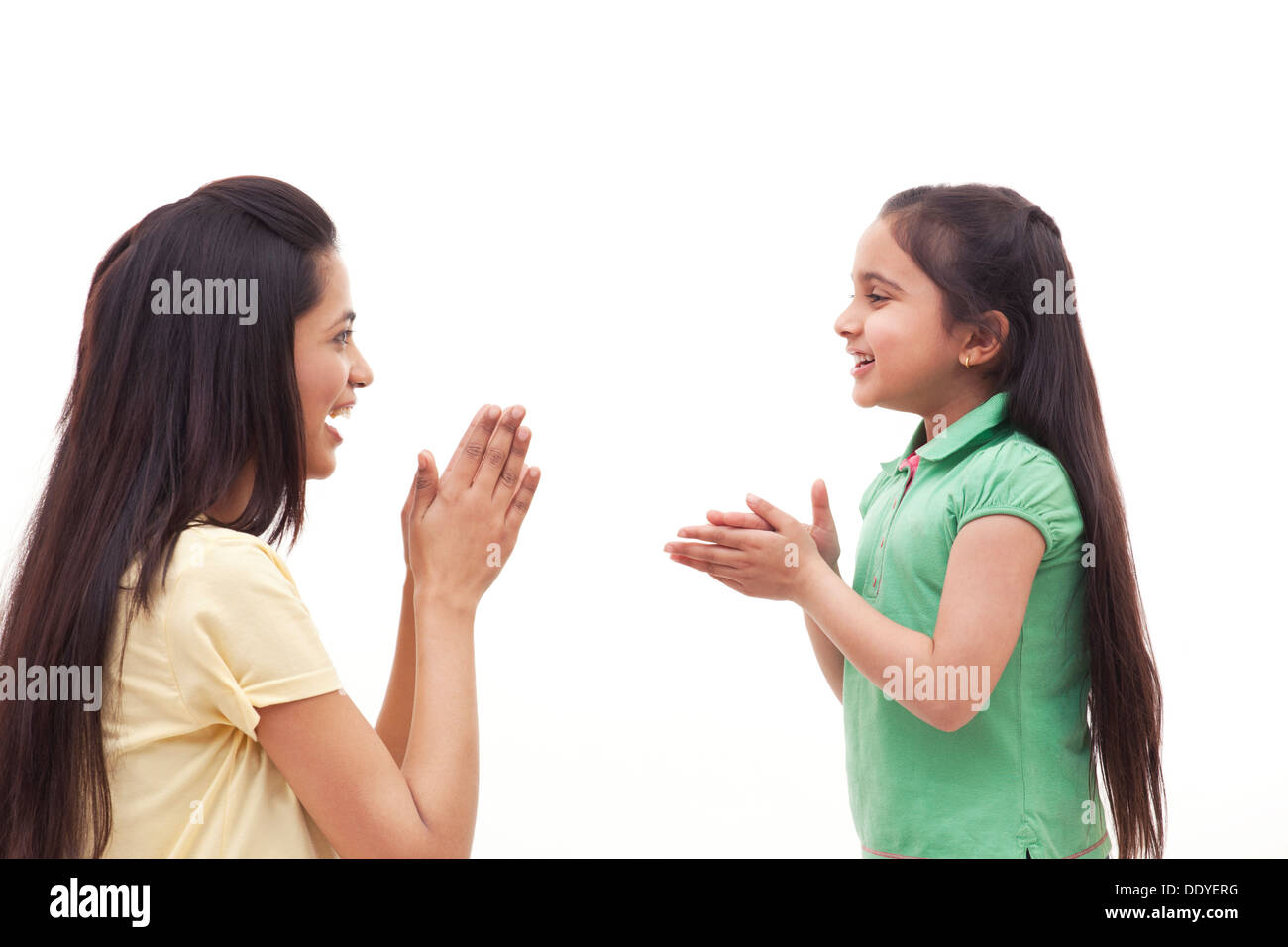 Side view of mother and daughter clapping over white background Stock ...