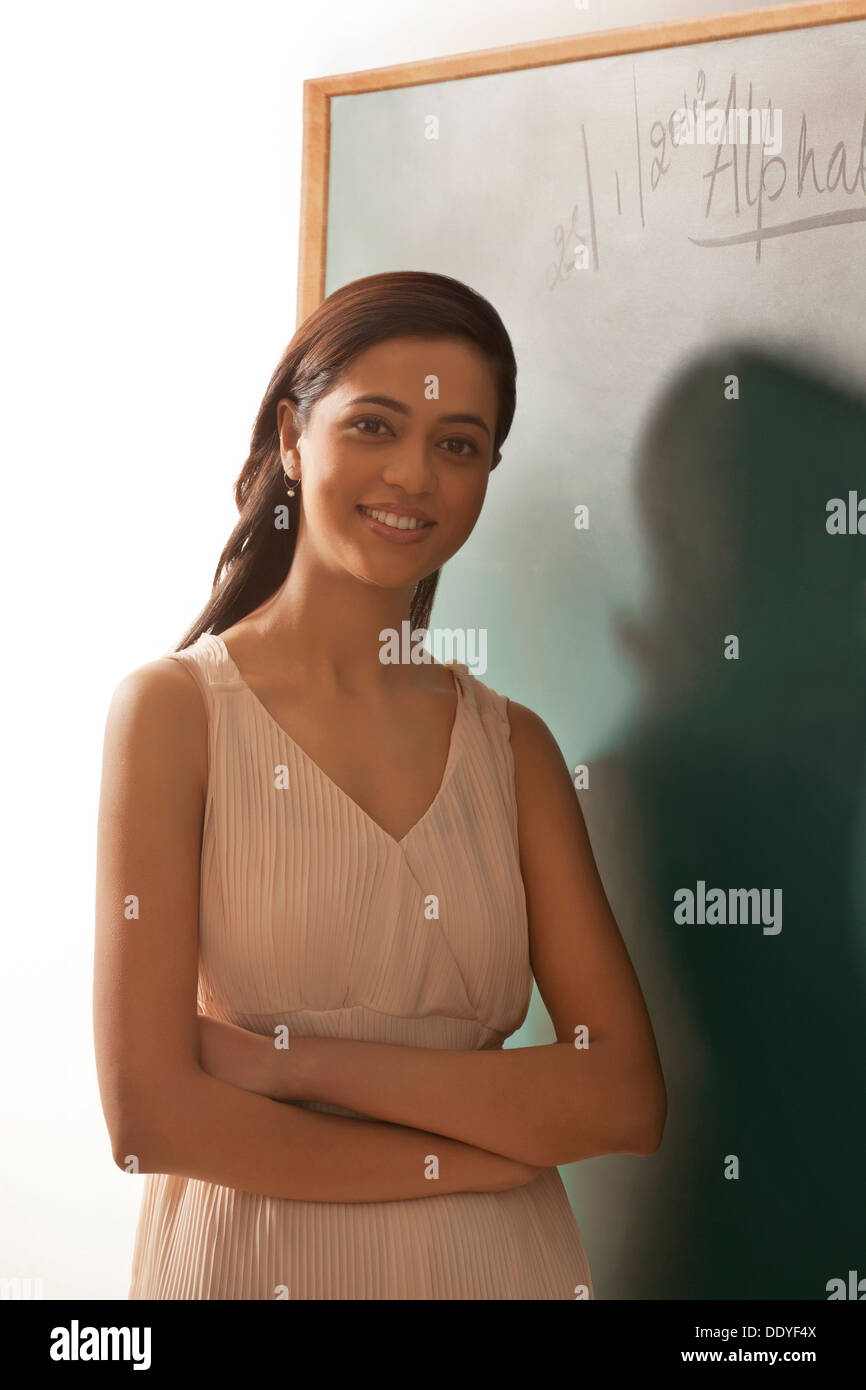 Young confident female teacher standing by green board Stock Photo - Alamy