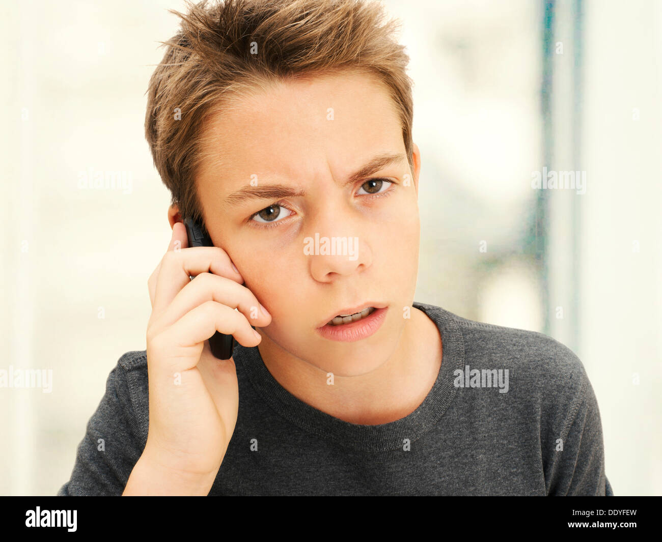 Portrait, boy, teenager looking angry while talking on a mobile phone ...