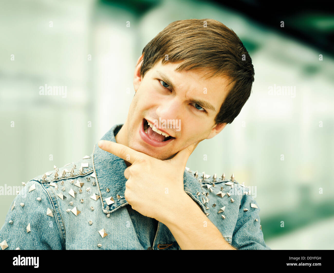 Young man with a serious face wearing a studded denim jacket, cheeky ...