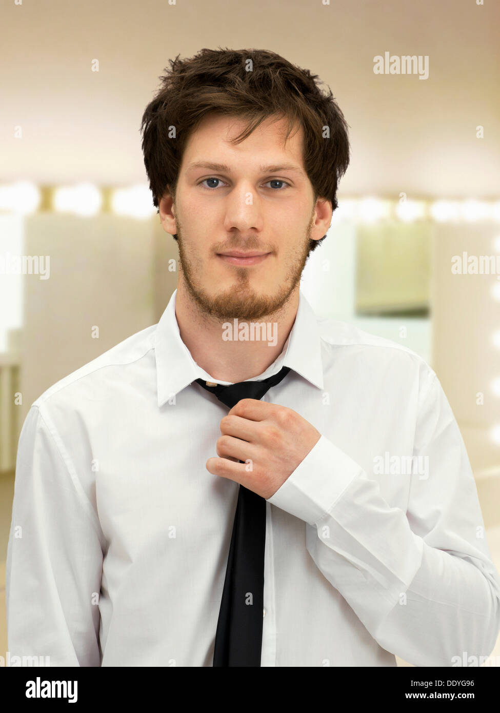 Portrait of a young man with a beard straightening his tie, friendly ...