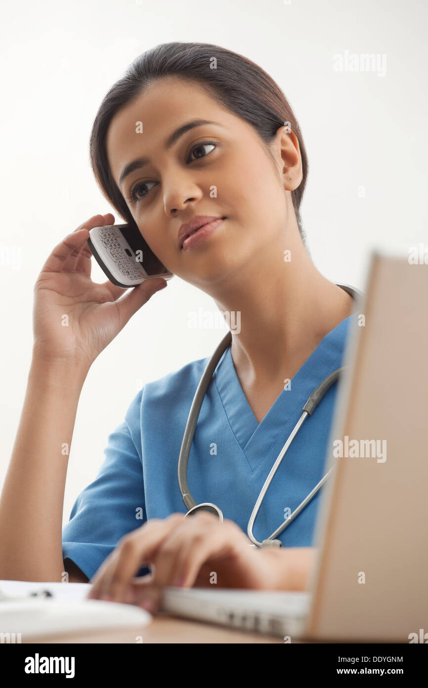 Young female surgeon using mobile phone at desk Stock Photo - Alamy