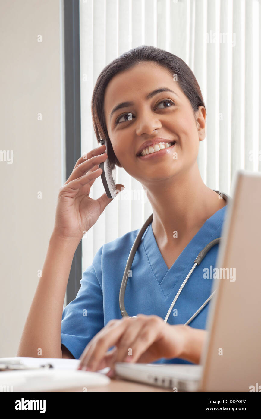 Happy young female surgeon using mobile phone at desk Stock Photo - Alamy