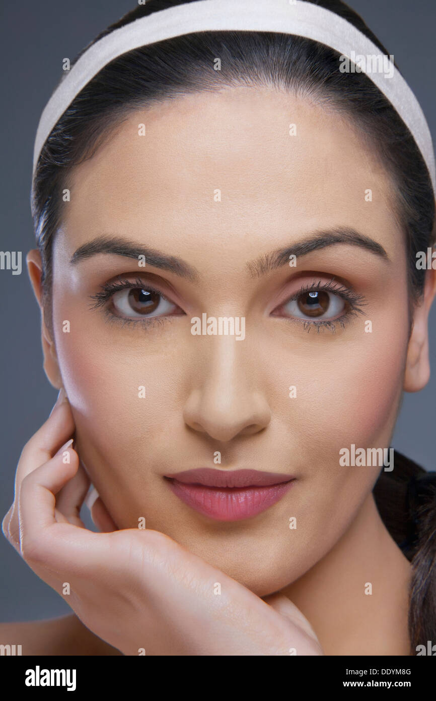 Portrait of a pretty female with hand on chin over colored background ...