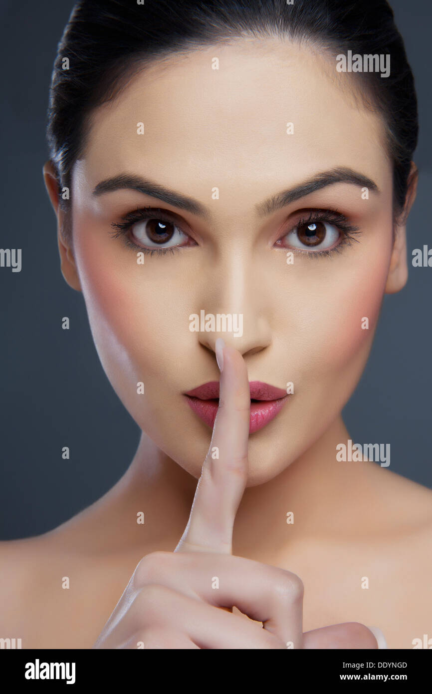 Portrait of a beautiful woman with finger on her lips over colored ...