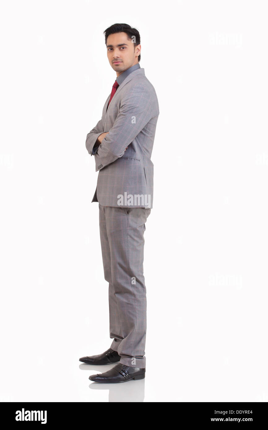 Side view of young businessman with arms crossed standing against white ...