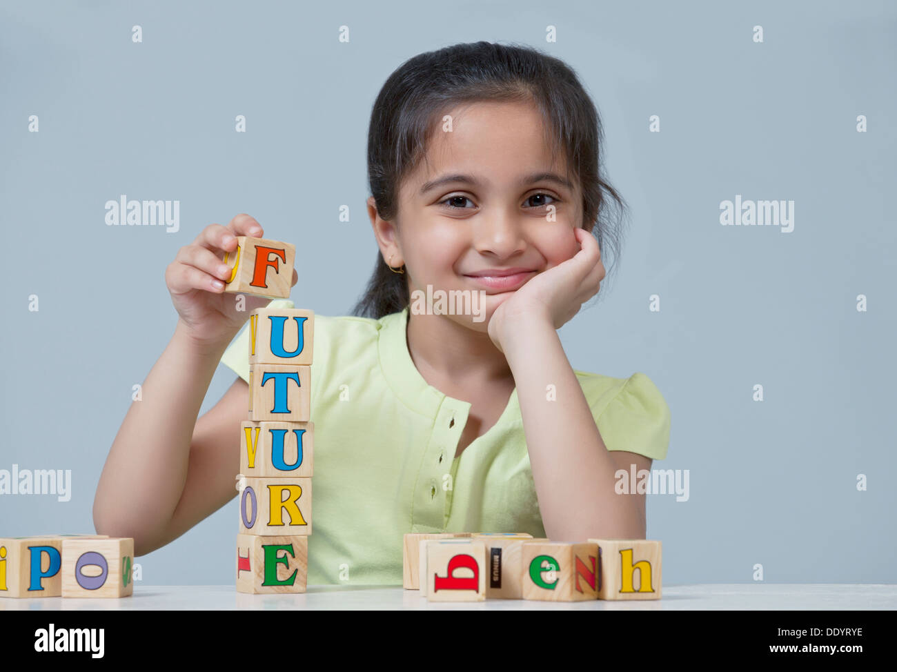 Portrait of little girl stacking blocks isolated over blue background ...