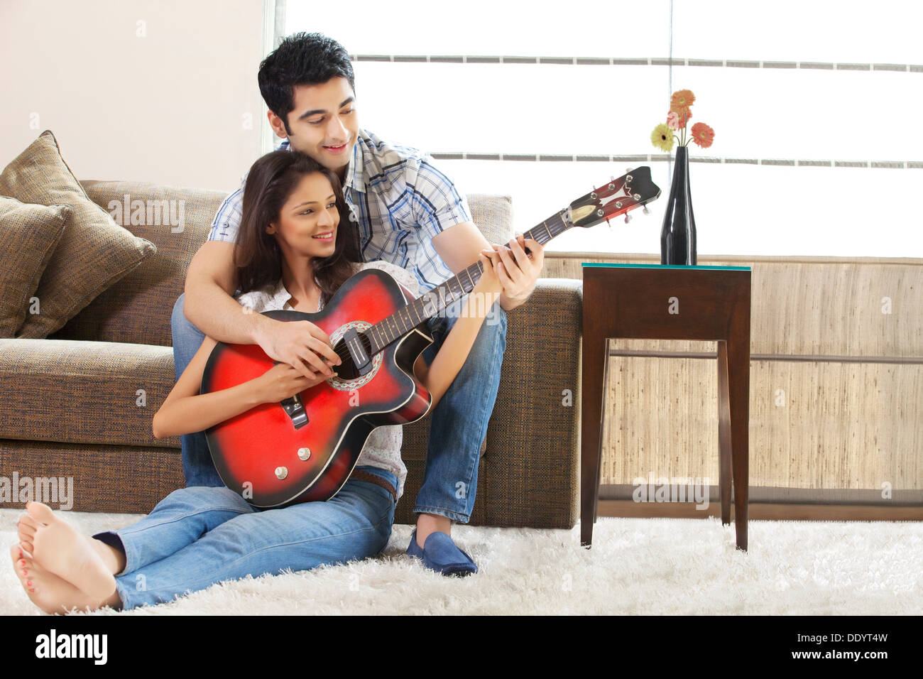 Relaxed young couple playing guitar together at home Stock Photo - Alamy