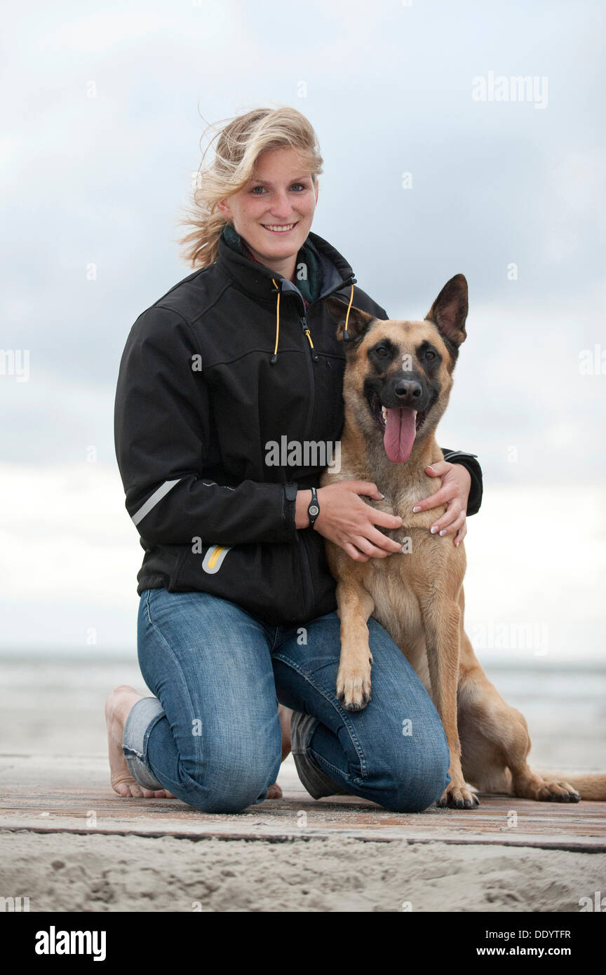 Woman with a Hollandse Herdershond, Dutch Shepherd, sitting on a beach ...