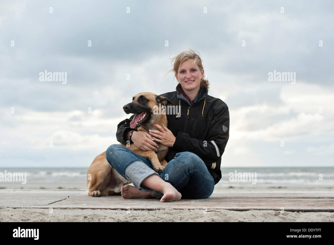 Woman with a Hollandse Herdershond, Dutch Shepherd, sitting on a beach ...