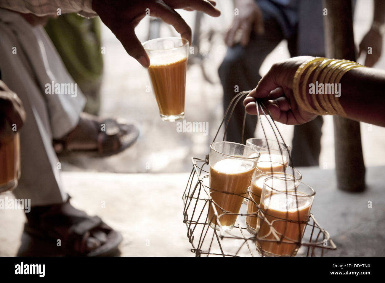Male hand taking a glass of chai from tray held by woman Stock Photo ...
