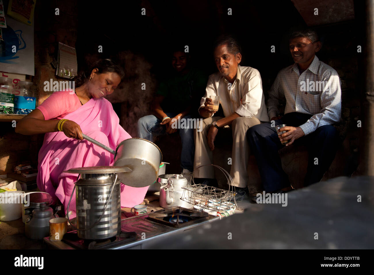 Indian female street tea vendor with customers sitting at stall Stock ...