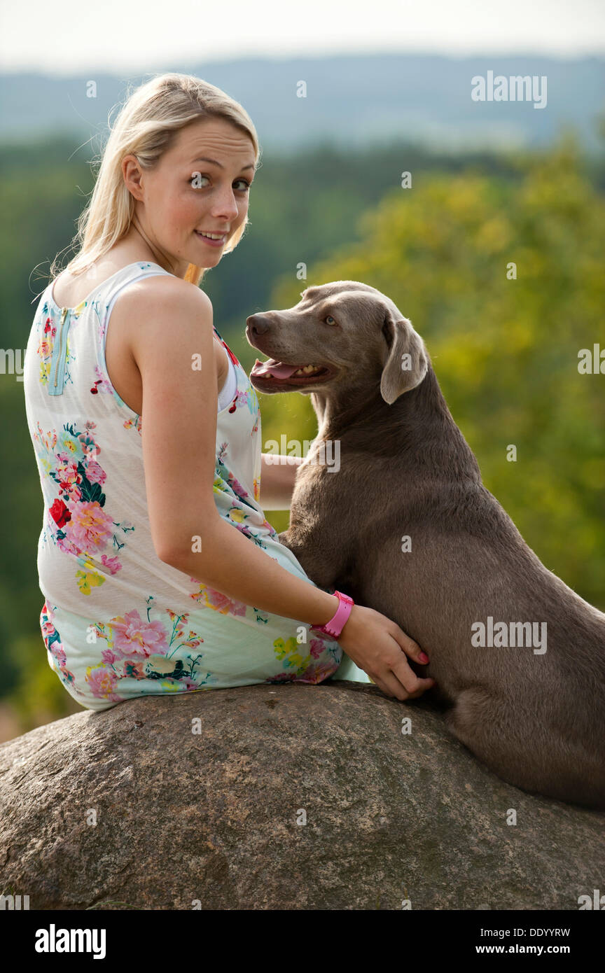 Woman sitting with a Labrador Retriever on a stone Stock Photo - Alamy