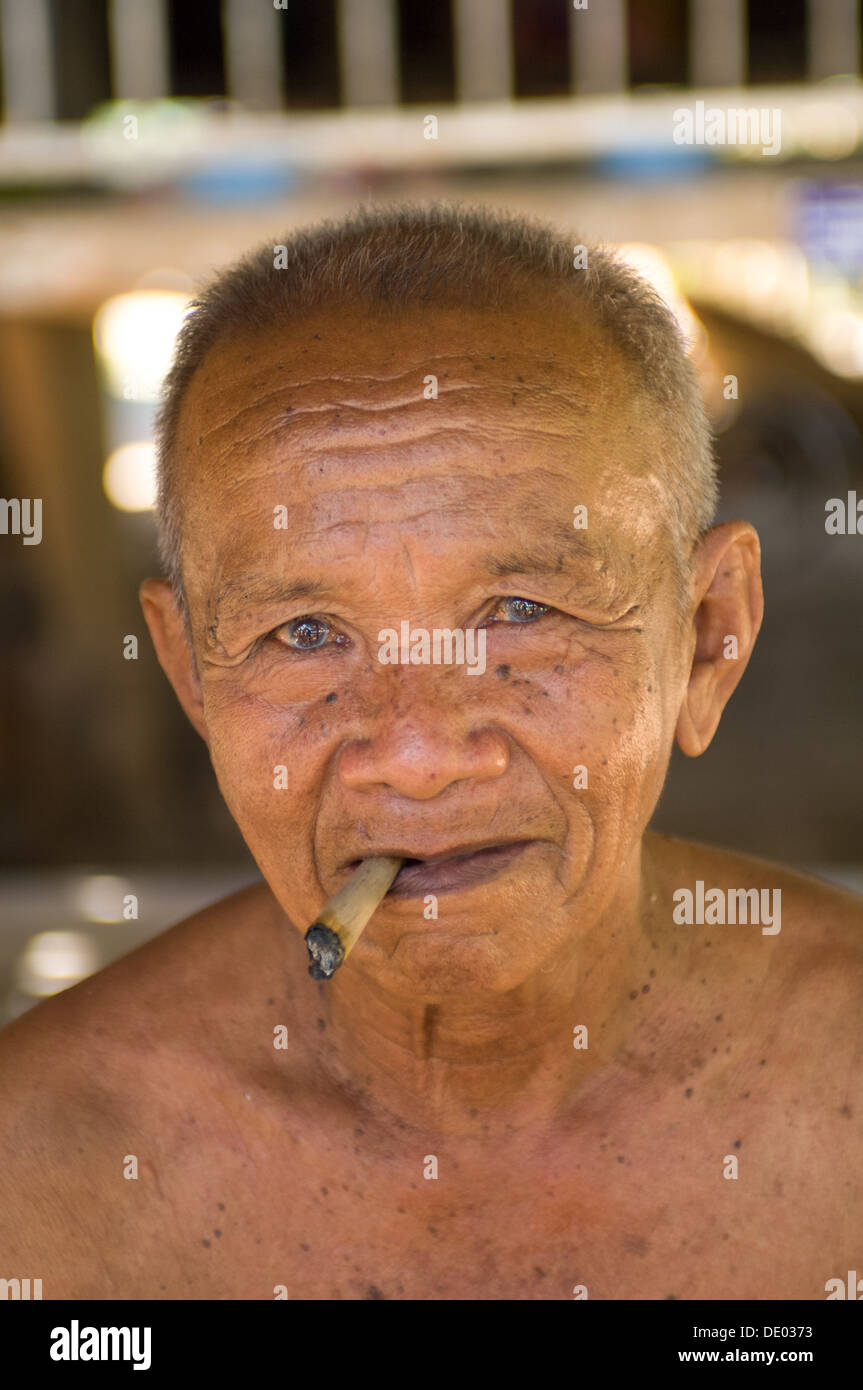 Elderly Laotian man smoking a self-rolled cigarette, Ban Hua Det ...