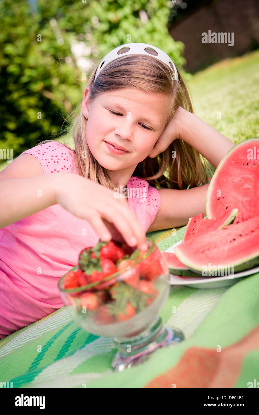 Girl eating strawberries in the garden Stock Photo - Alamy
