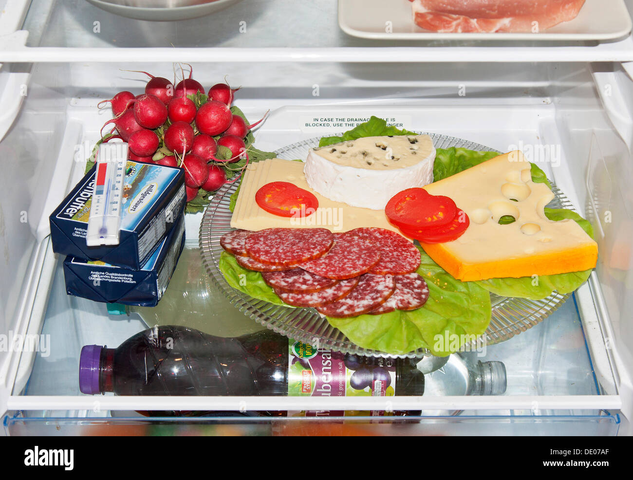 Wrong food storage in a fridge, uncovered cheese platter, sausage ...