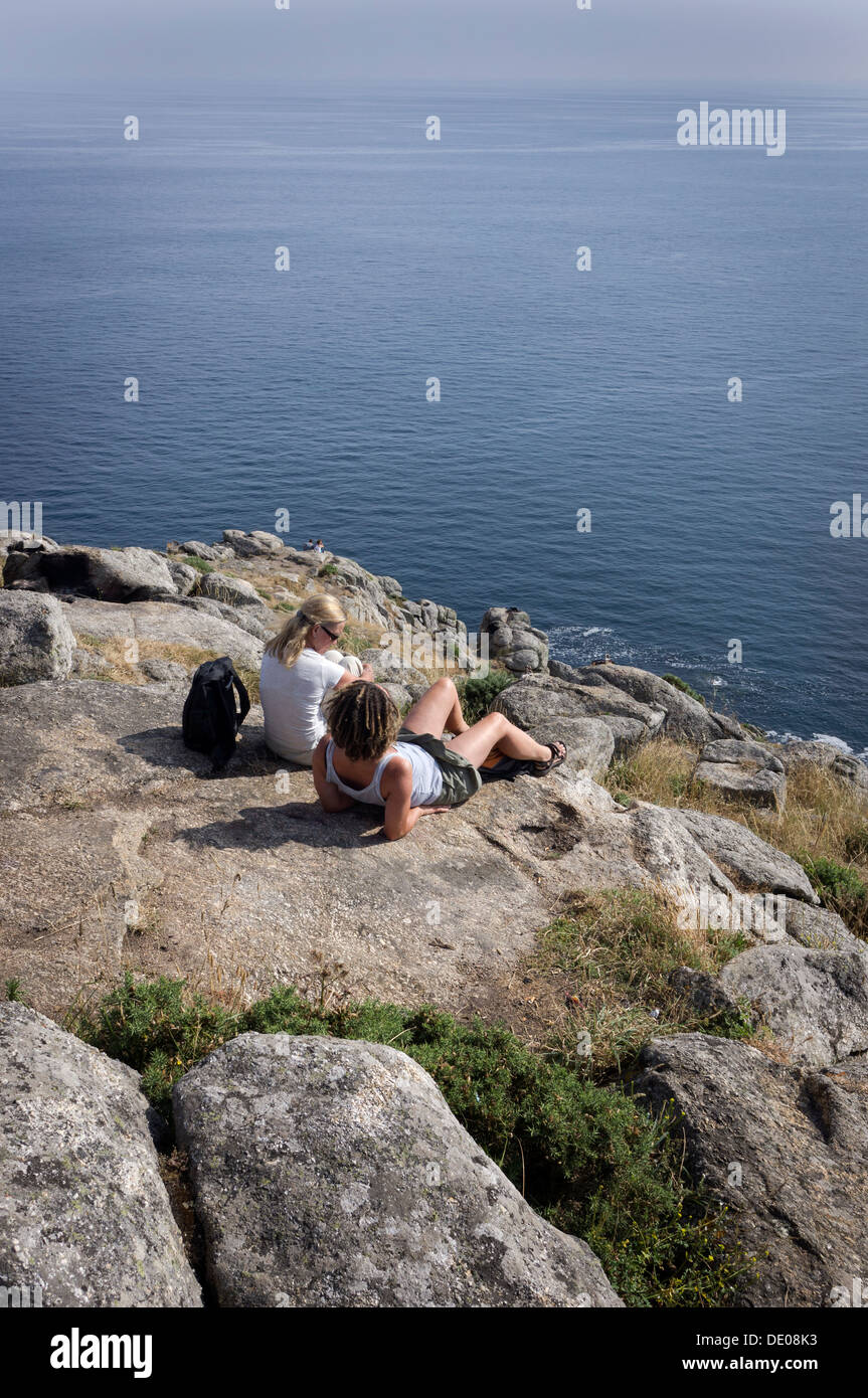 Two pilgrims sitting on the cliffs near the lighthouse of Finisterre ...