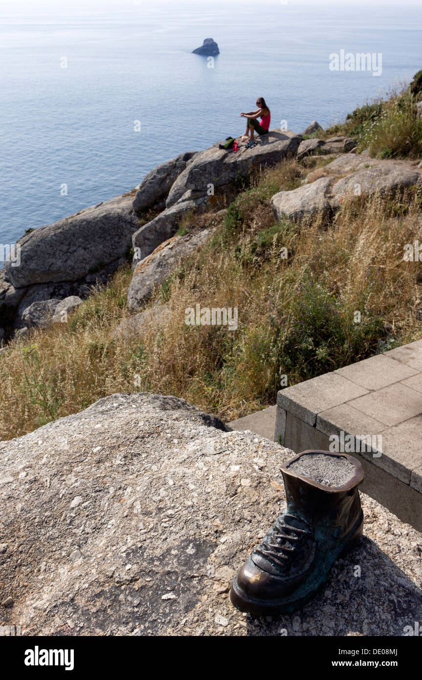 A tourist sits on the cliffs near the lighthouse of Finisterre, the end ...