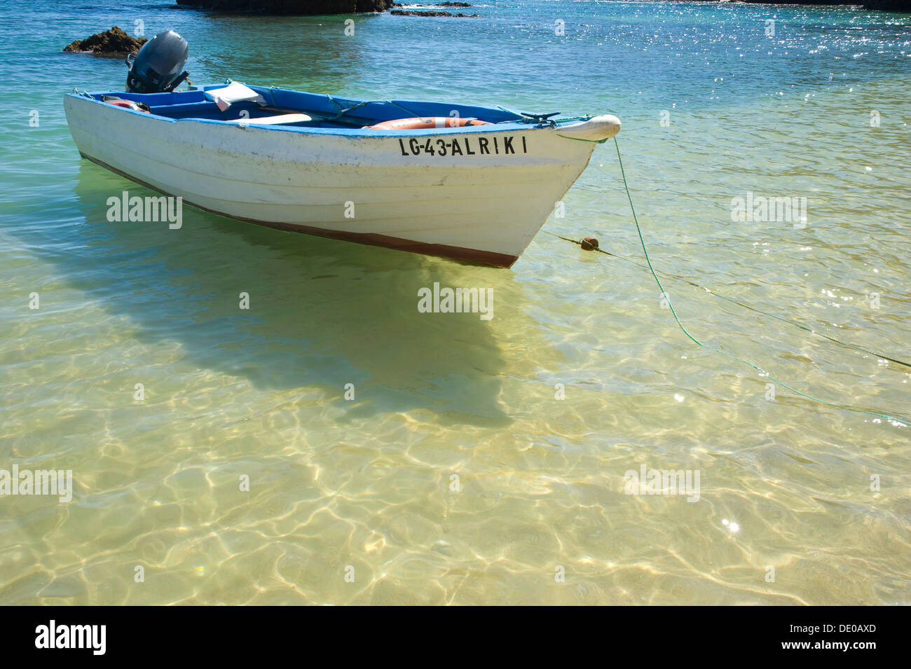 A small motorized dinghy floating in shallow water on the shore in the ...