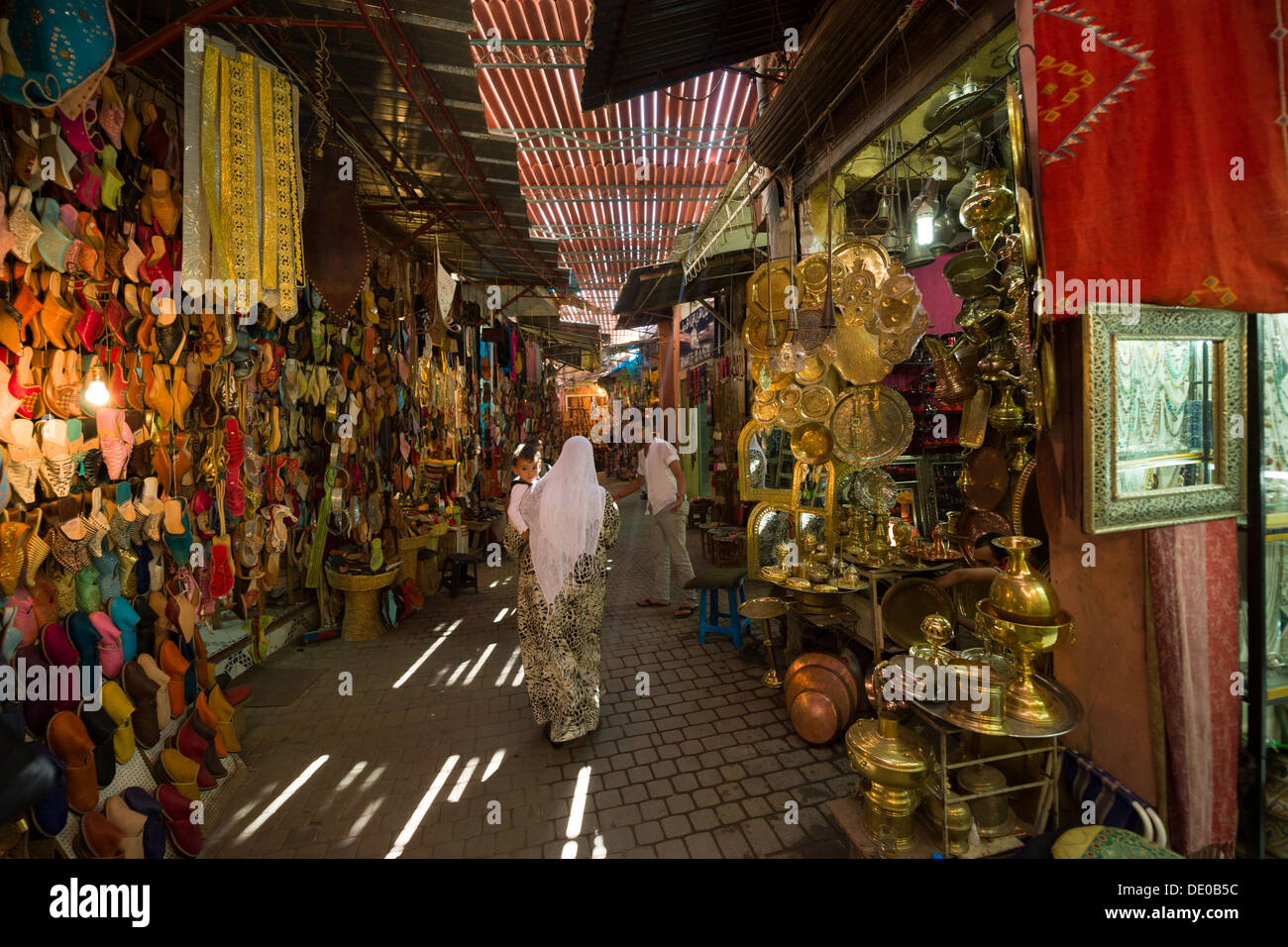 Moroccan woman in traditional dress being approached by a shopkeeper as ...