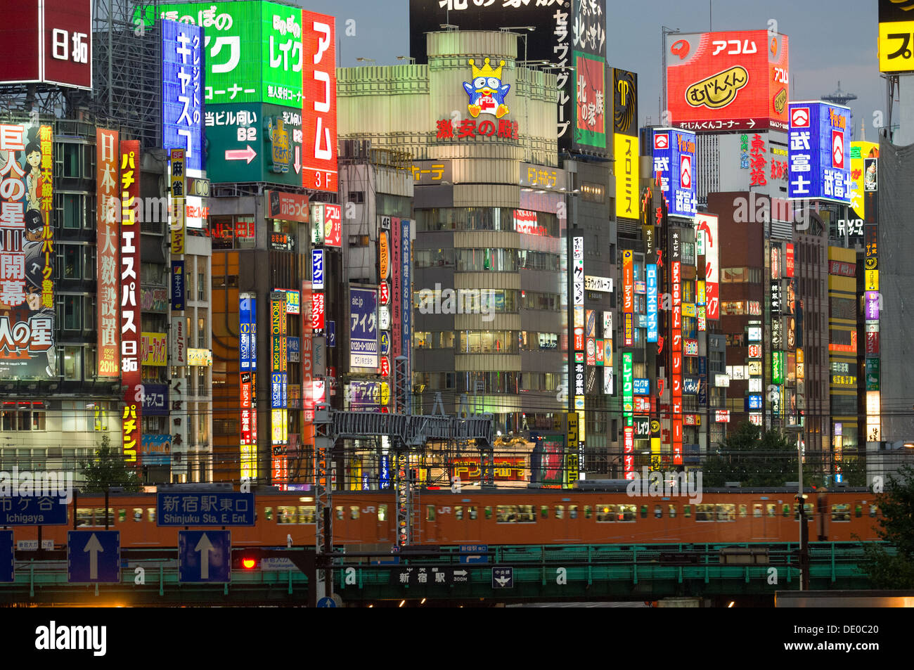 Train passing buildings lit with neon advertising signs, Shinjuku ...