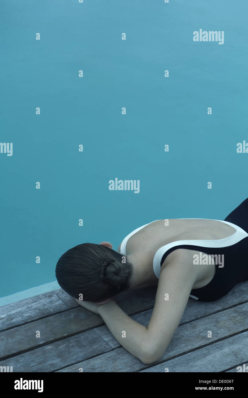 Woman in bathing suit lying on deck next to pool Stock Photo - Alamy