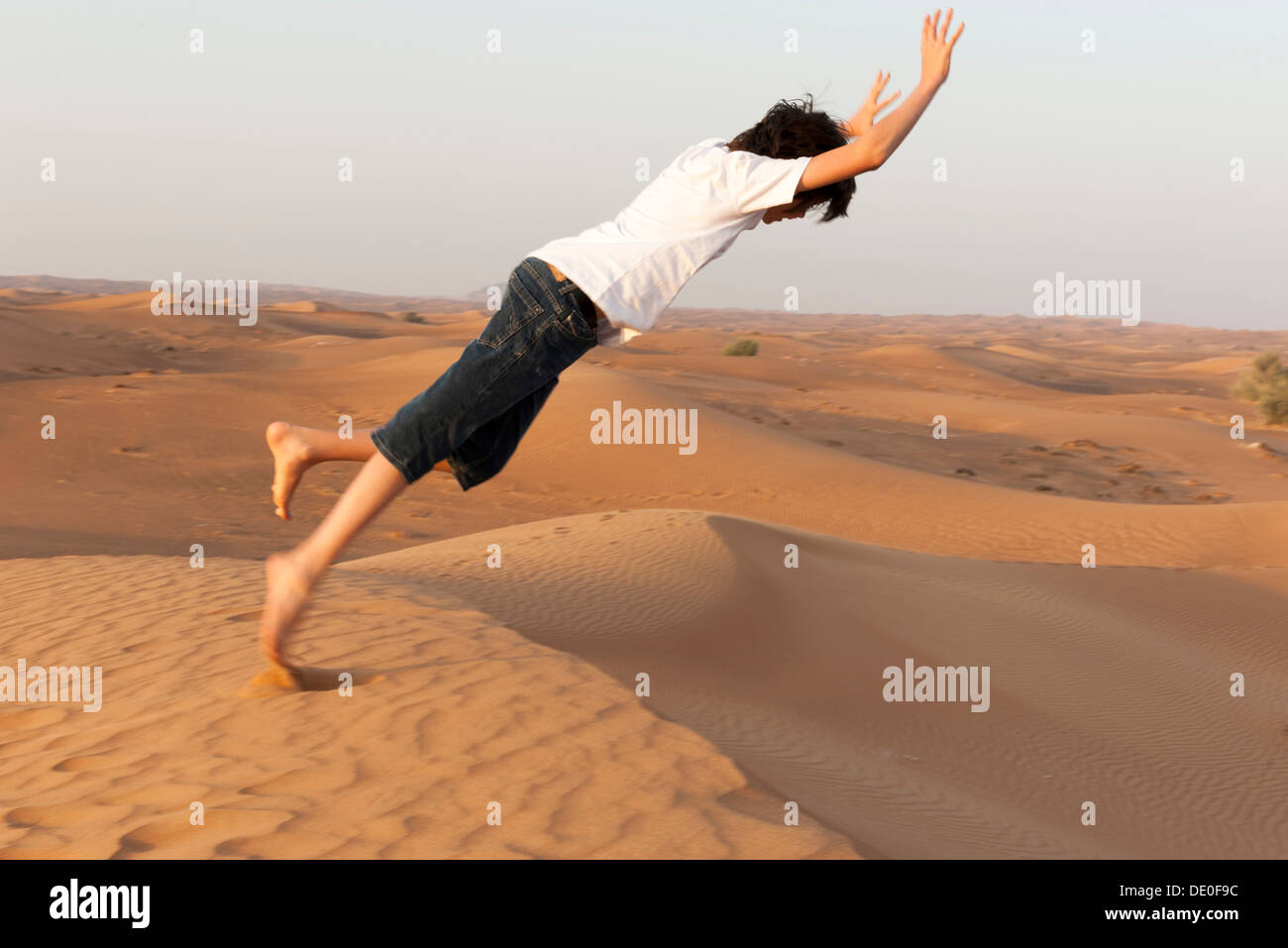 Teenage boy pretending to fall from top of desert sand dune Stock Photo ...