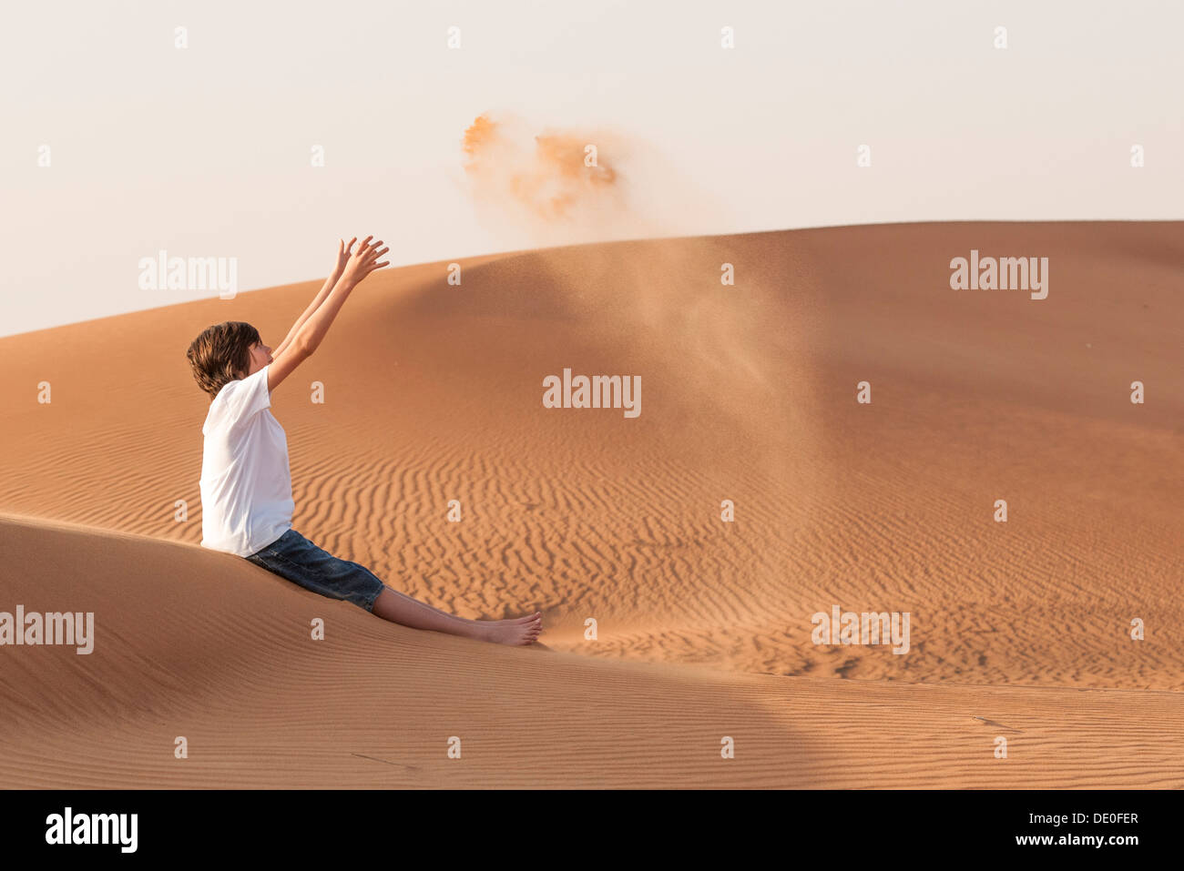 Teenage boy playfully tossing sand into air Stock Photo - Alamy