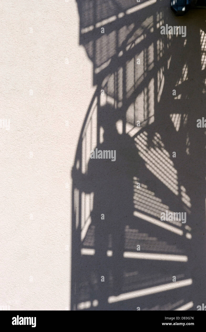 Shadow of a circular staircase made of metal on an exterior wall of a ...