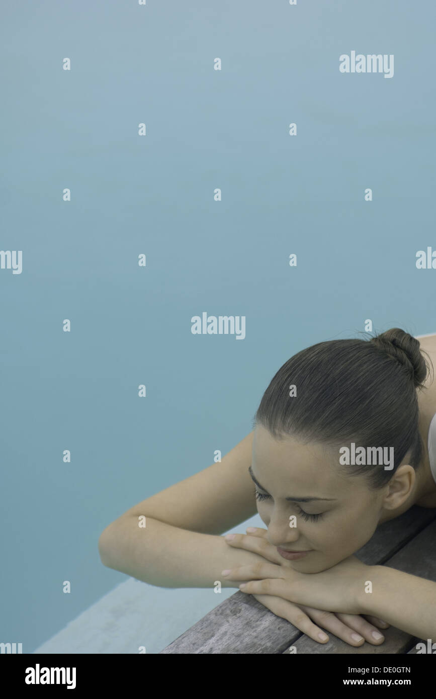 Woman lying next to pool, resting head on arms, eyes closed Stock Photo ...