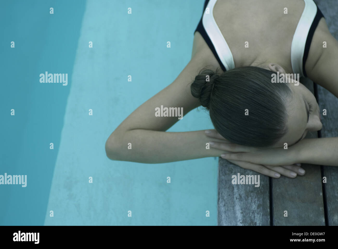 Woman lying on deck next to pool, resting head on arms Stock Photo - Alamy