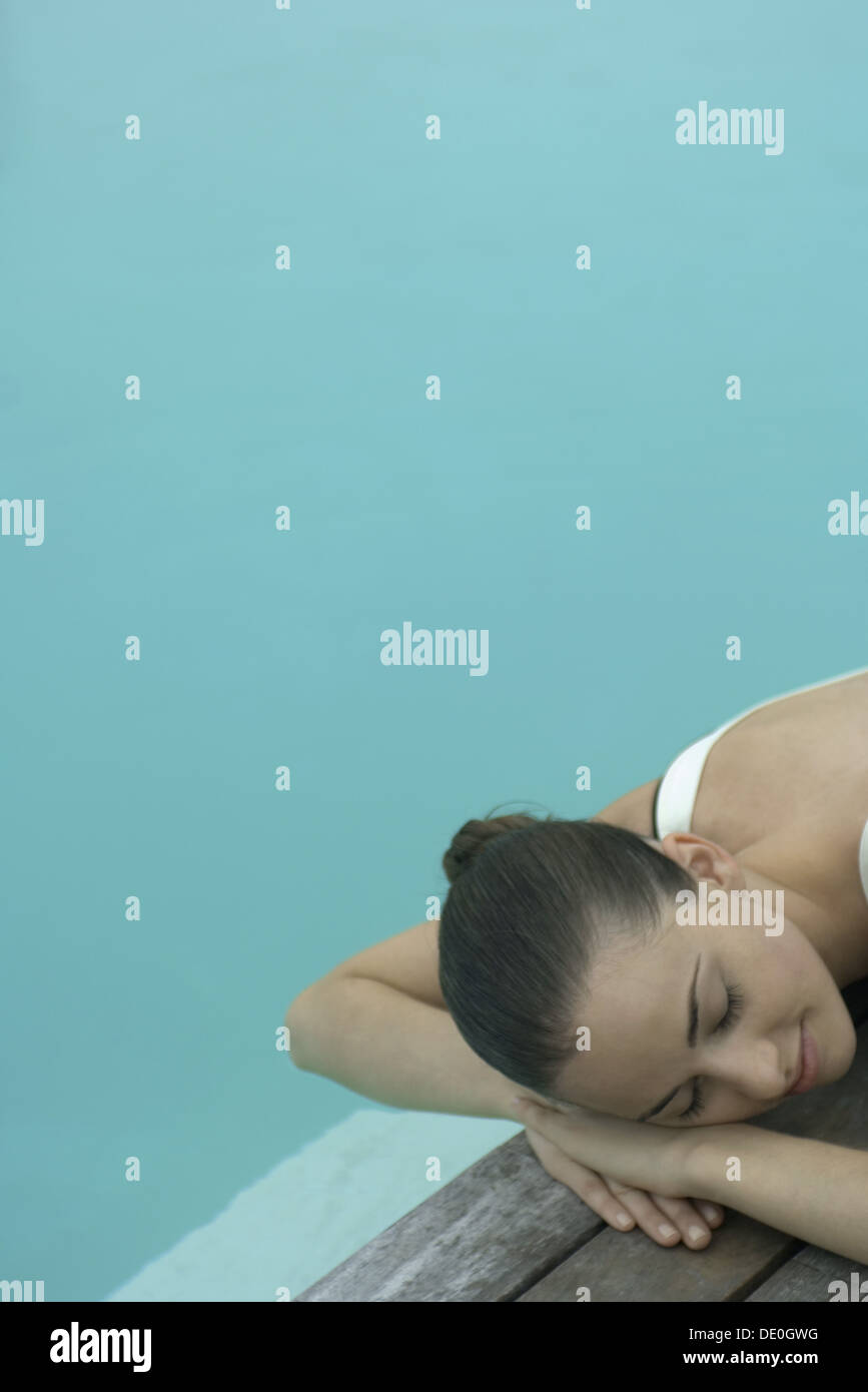 Woman lying next to pool, resting head on arms, eyes closed Stock Photo ...