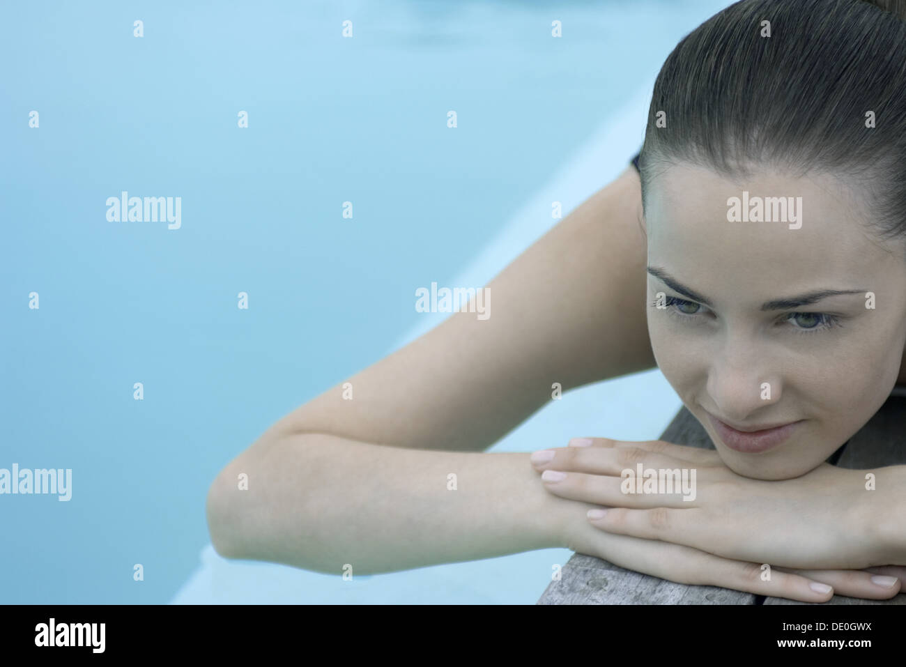 Woman lying next to pool, resting head on arms, looking away Stock ...