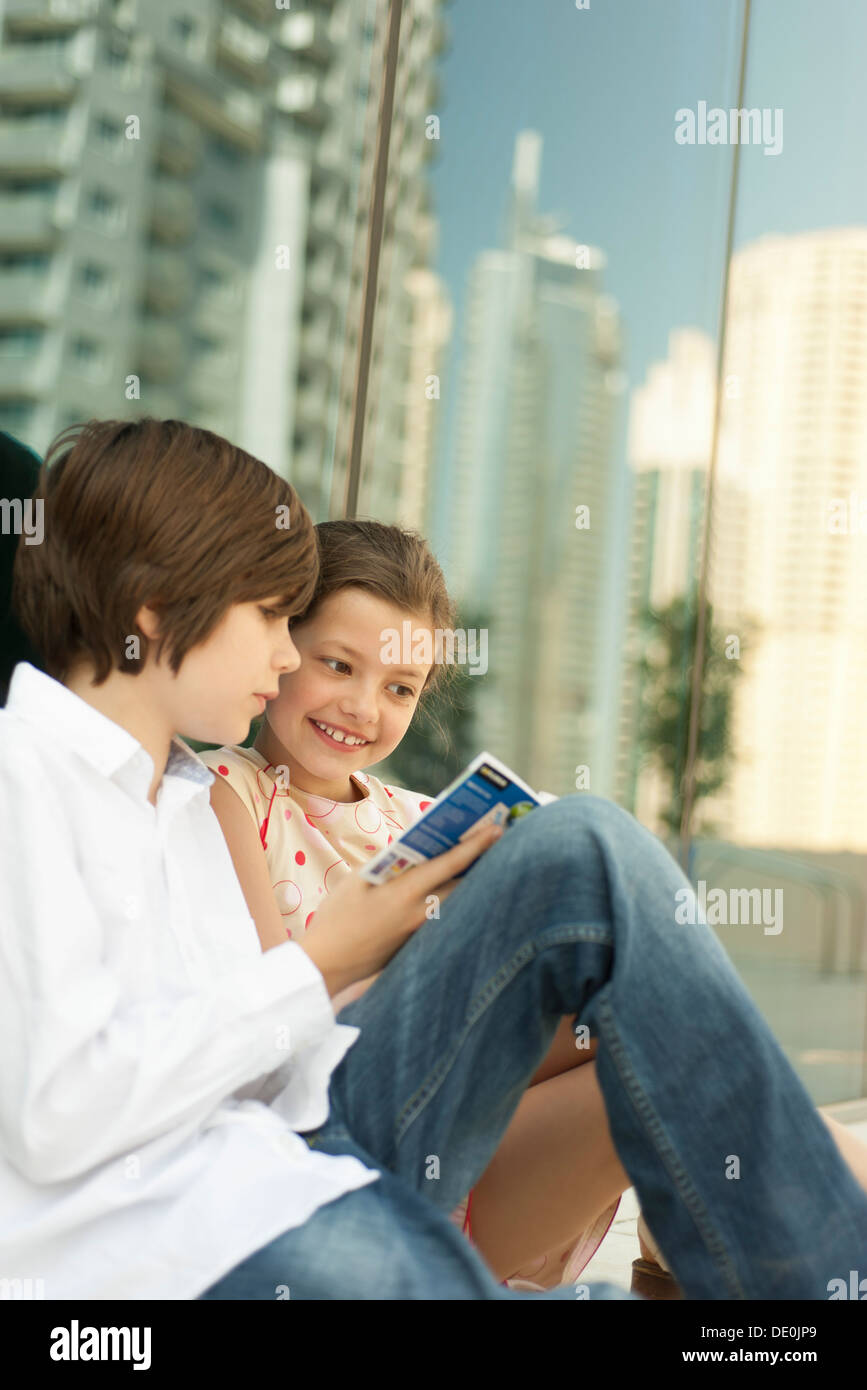 Brother and sister reading guidebook together Stock Photo - Alamy